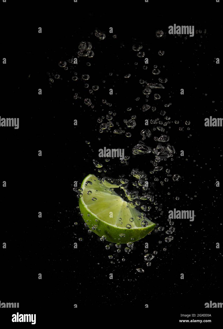 Lime splashing in water on a black background Stock Photo - Alamy