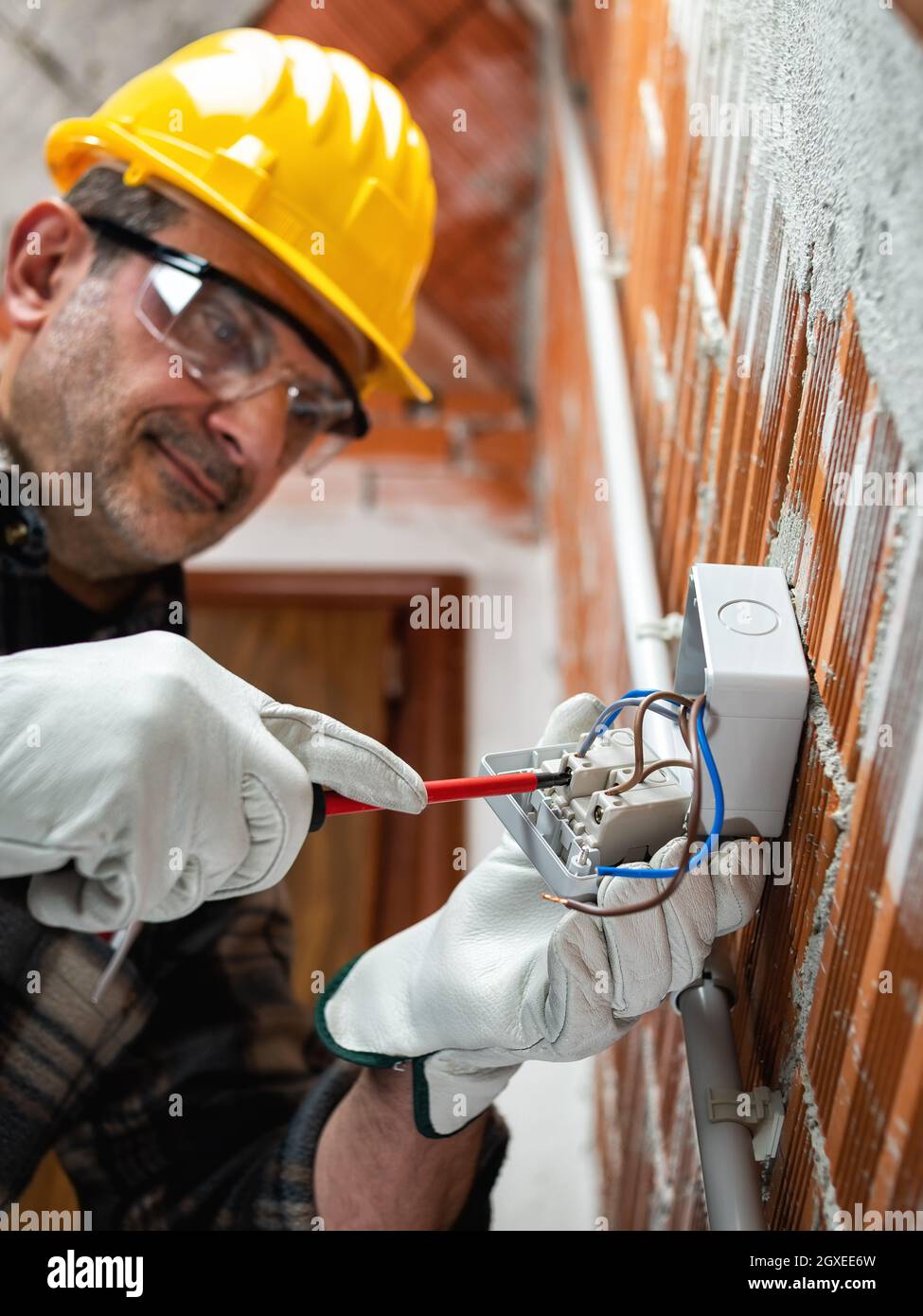 Electrician worker with a screwdriver fixes the cable in the switch of ...