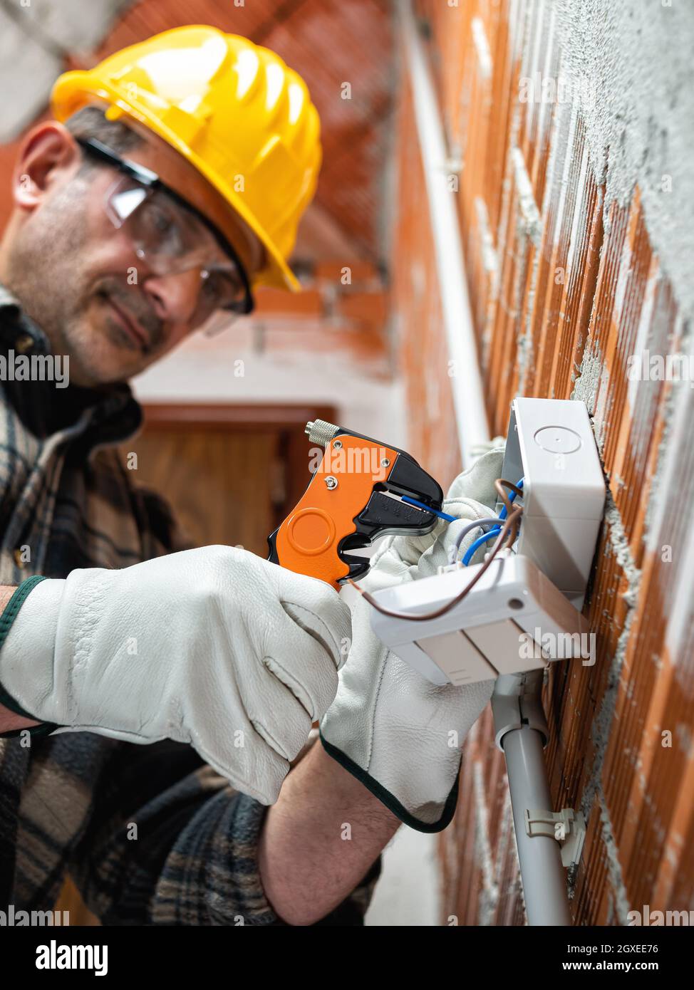 Electrician worker with wire stripper prepares electrical cables; wear ...