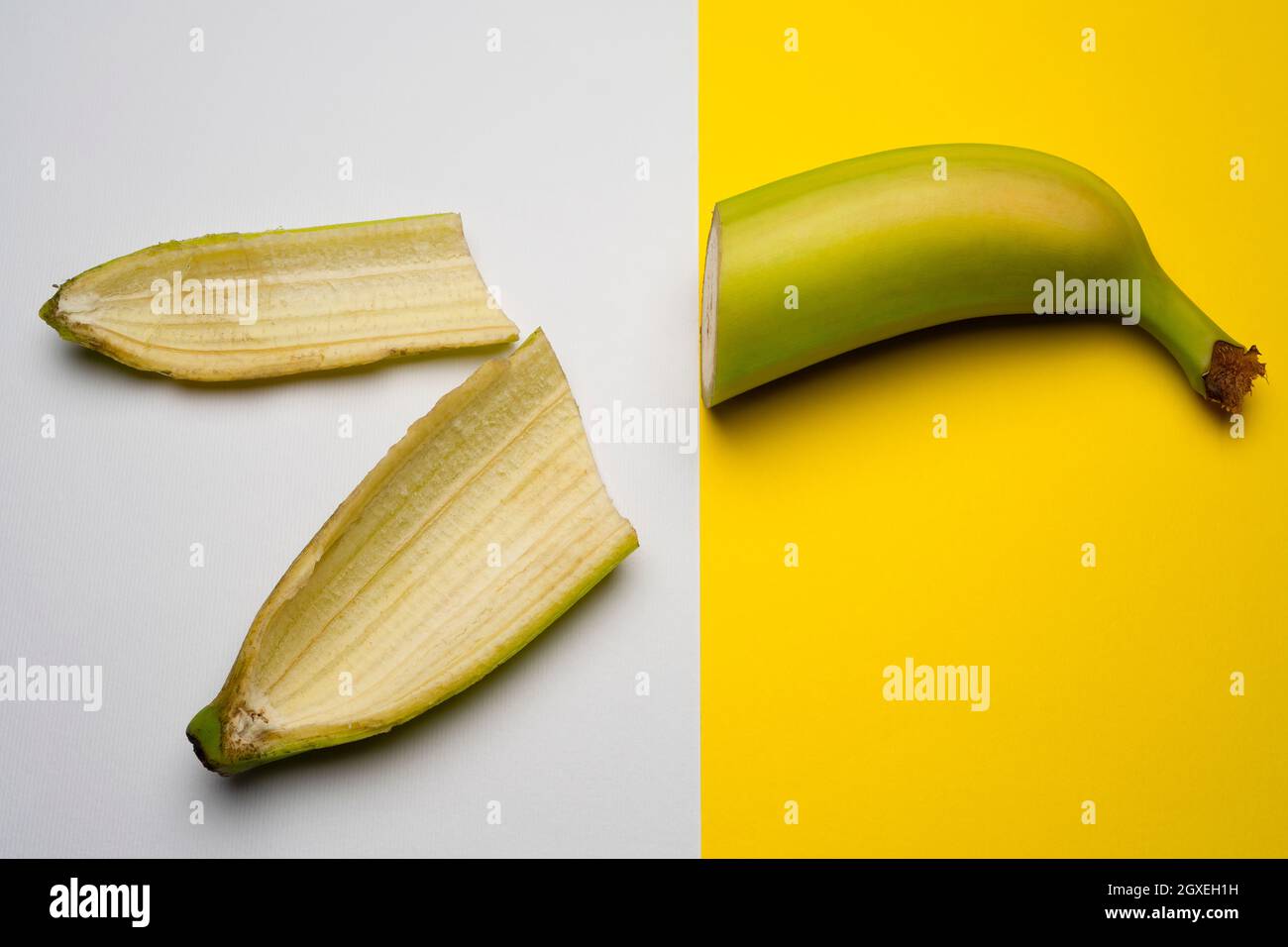 the banana cut in half and the peel on a colored surface Stock Photo ...