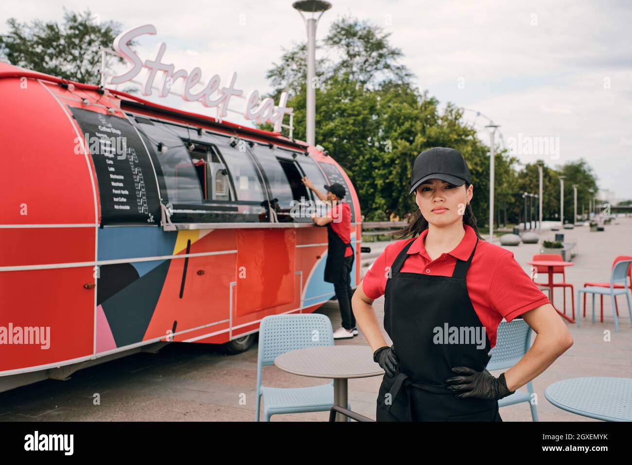 Young female owner of street food truck standing in front of camera ...