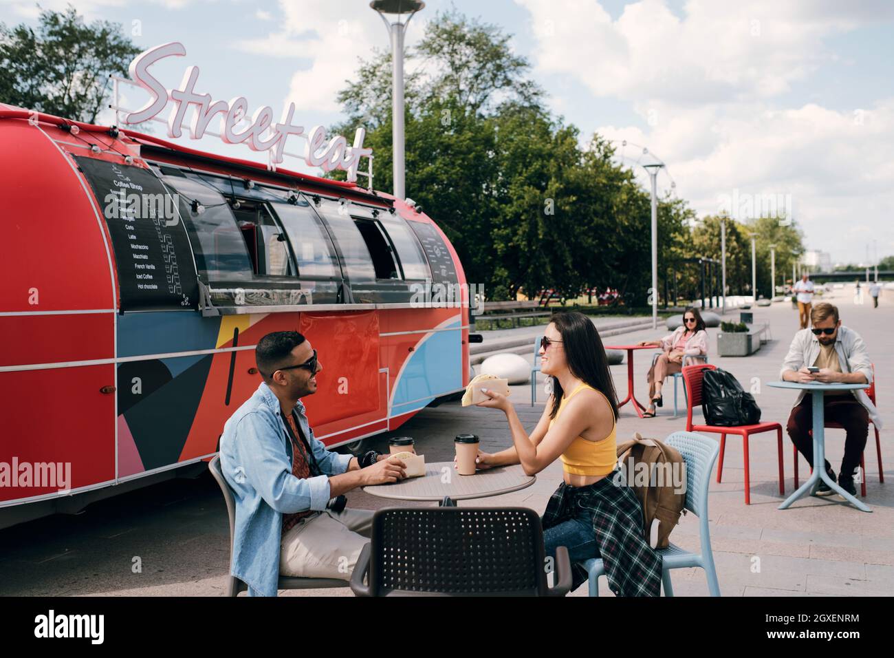 Happy young couple interacting by table in outdoor cafe while having ...