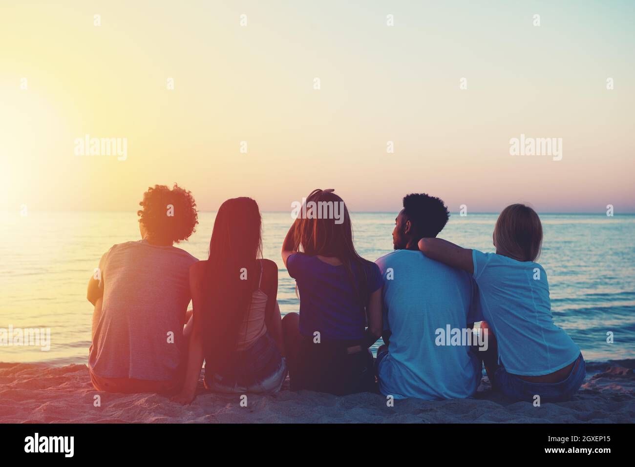 Group of happy friends relaxing at the beach during sunset Stock Photo ...