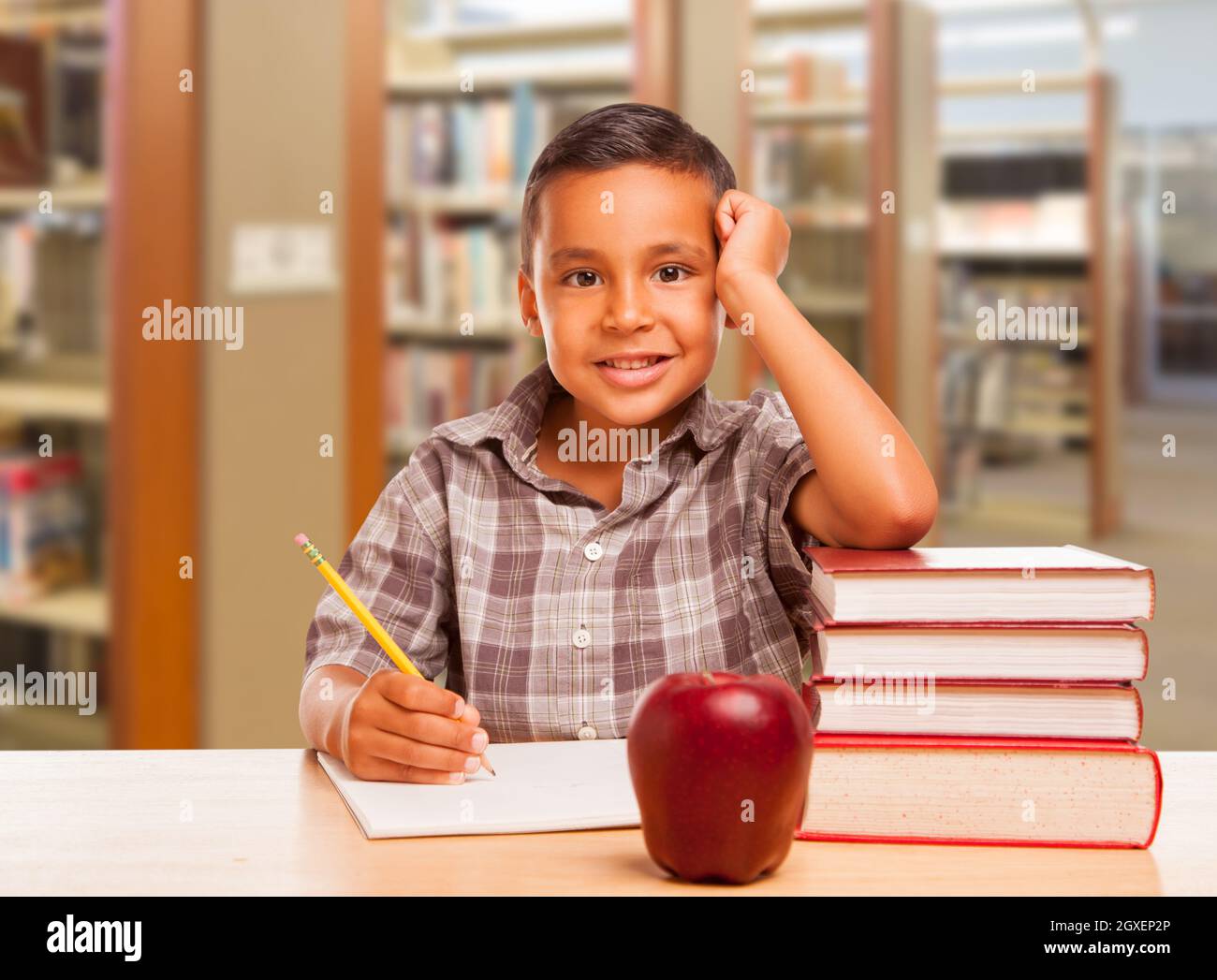 Adorable Hispanic Boy with Books, Apple, Pencil and Paper Studying at ...