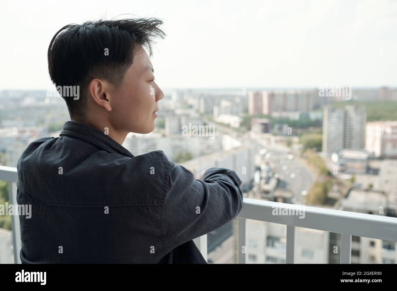 Back view of young Chinese woman standing on balcony in front of ...
