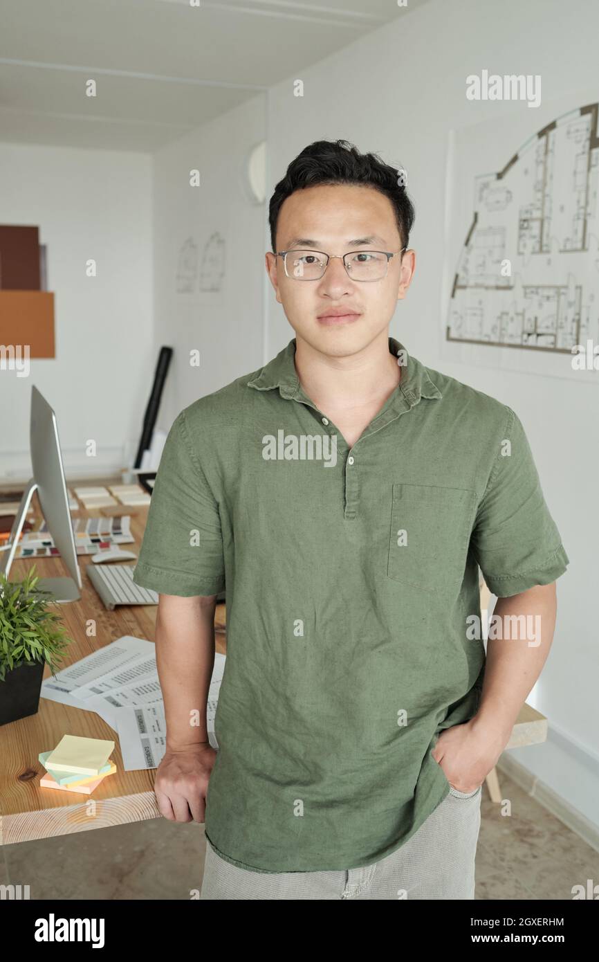 Young professional designer standing against his workplace with ...