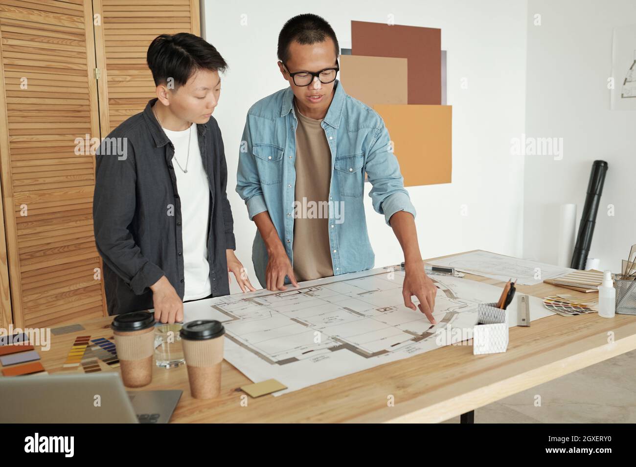 Two young Chinese engineers in casualwear discussing sketch on ...
