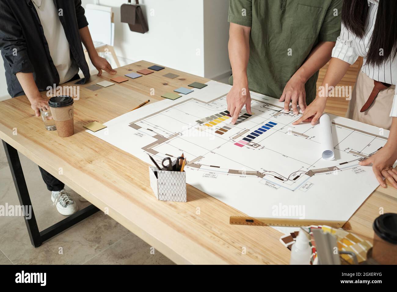 Team of contemporary engineers discussing color palette over blueprint ...