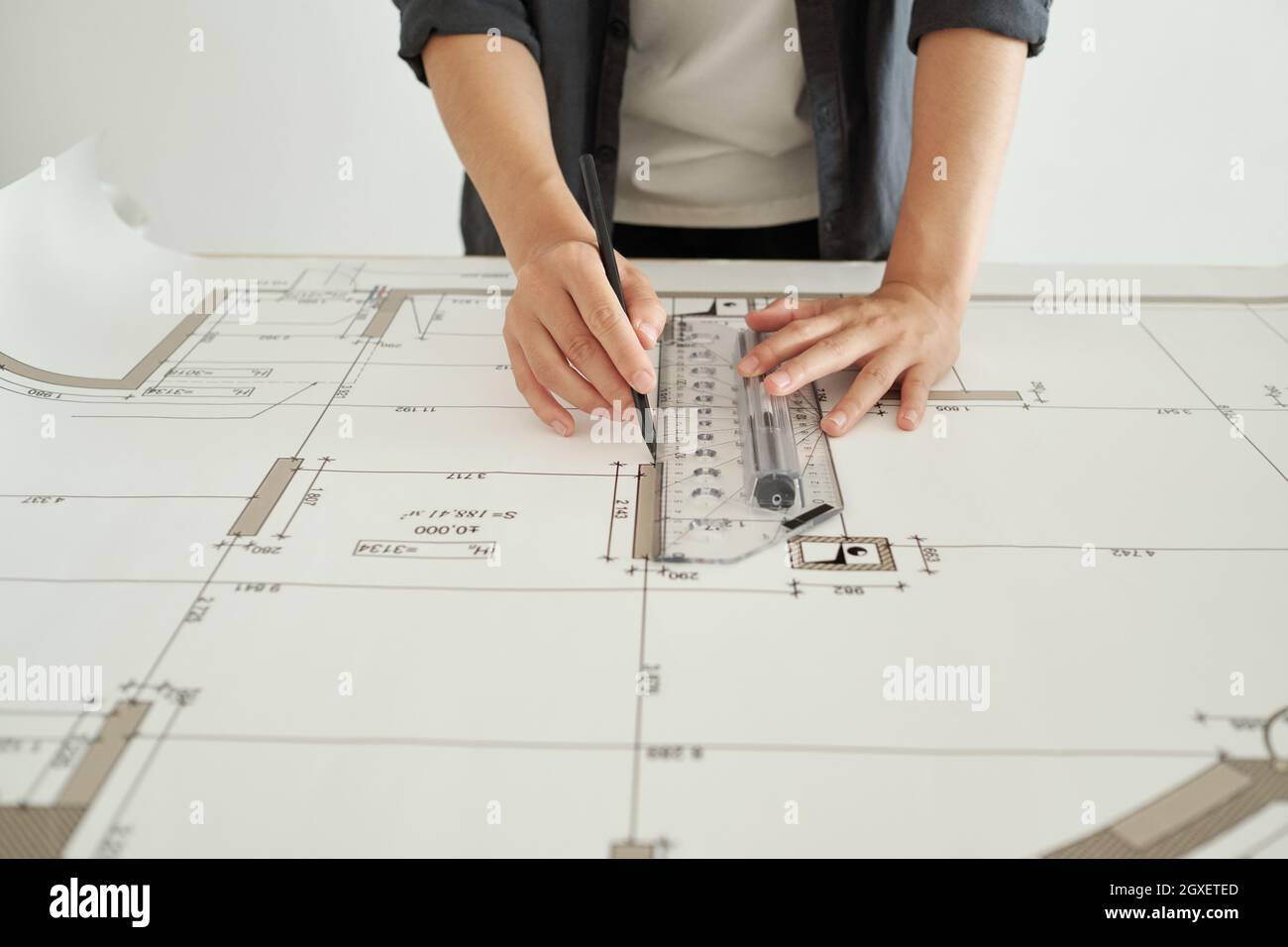 Hands of young contemporary engineer with pencil and ruler drawing line ...