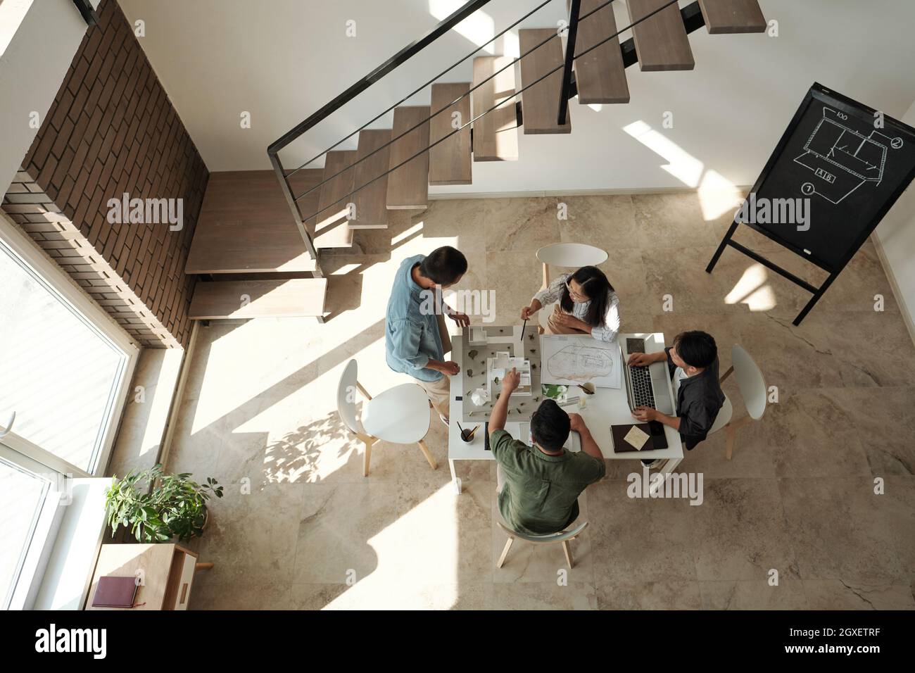 Group of young Chinese architects gathered by table for discussion of ...
