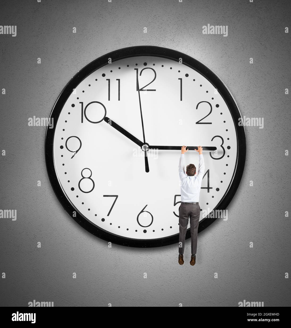 Concept of time with a businessman hanging from the hands of a clock ...