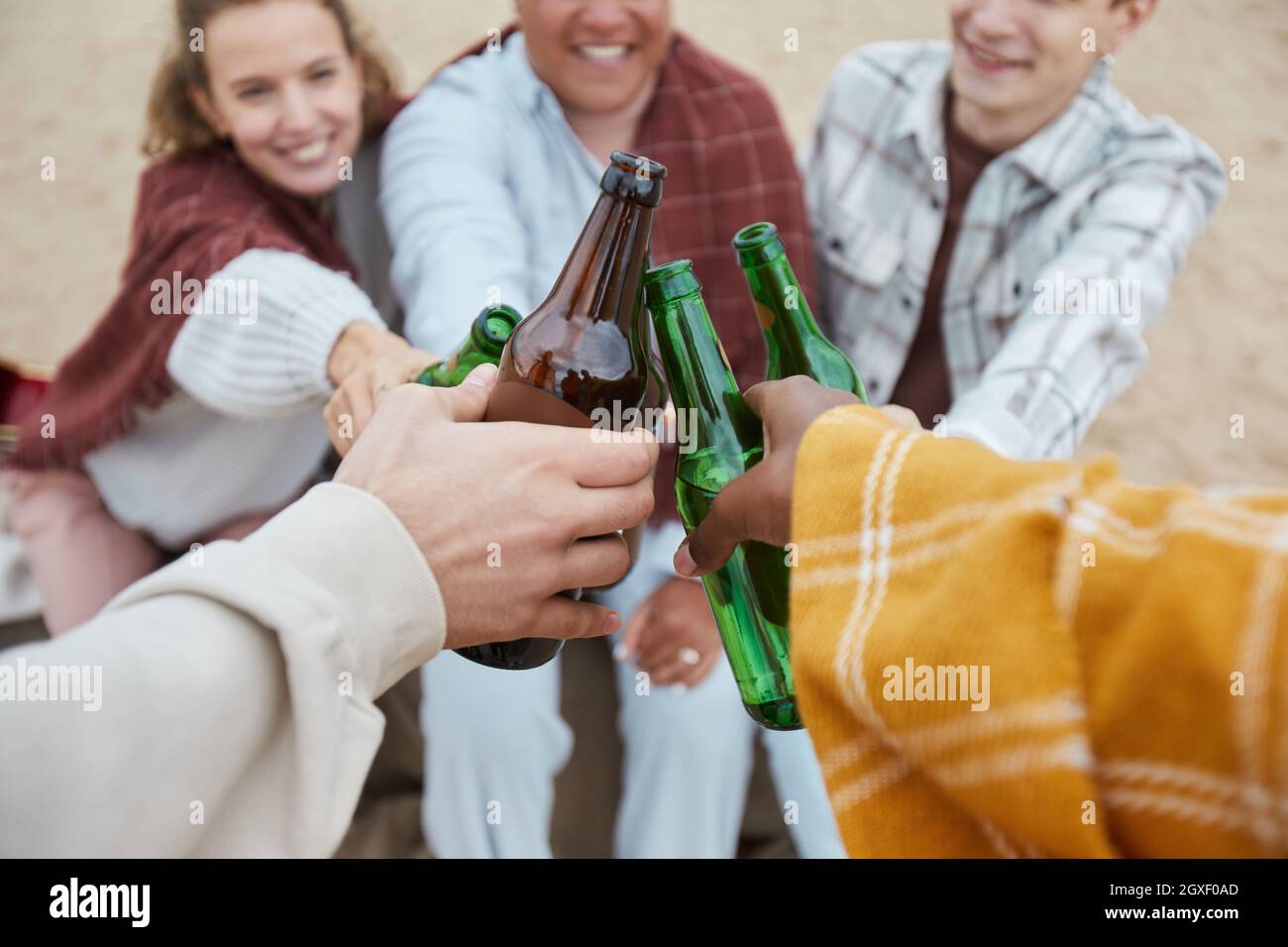 Close up of young people clinking beer bottles while enjoying camping ...