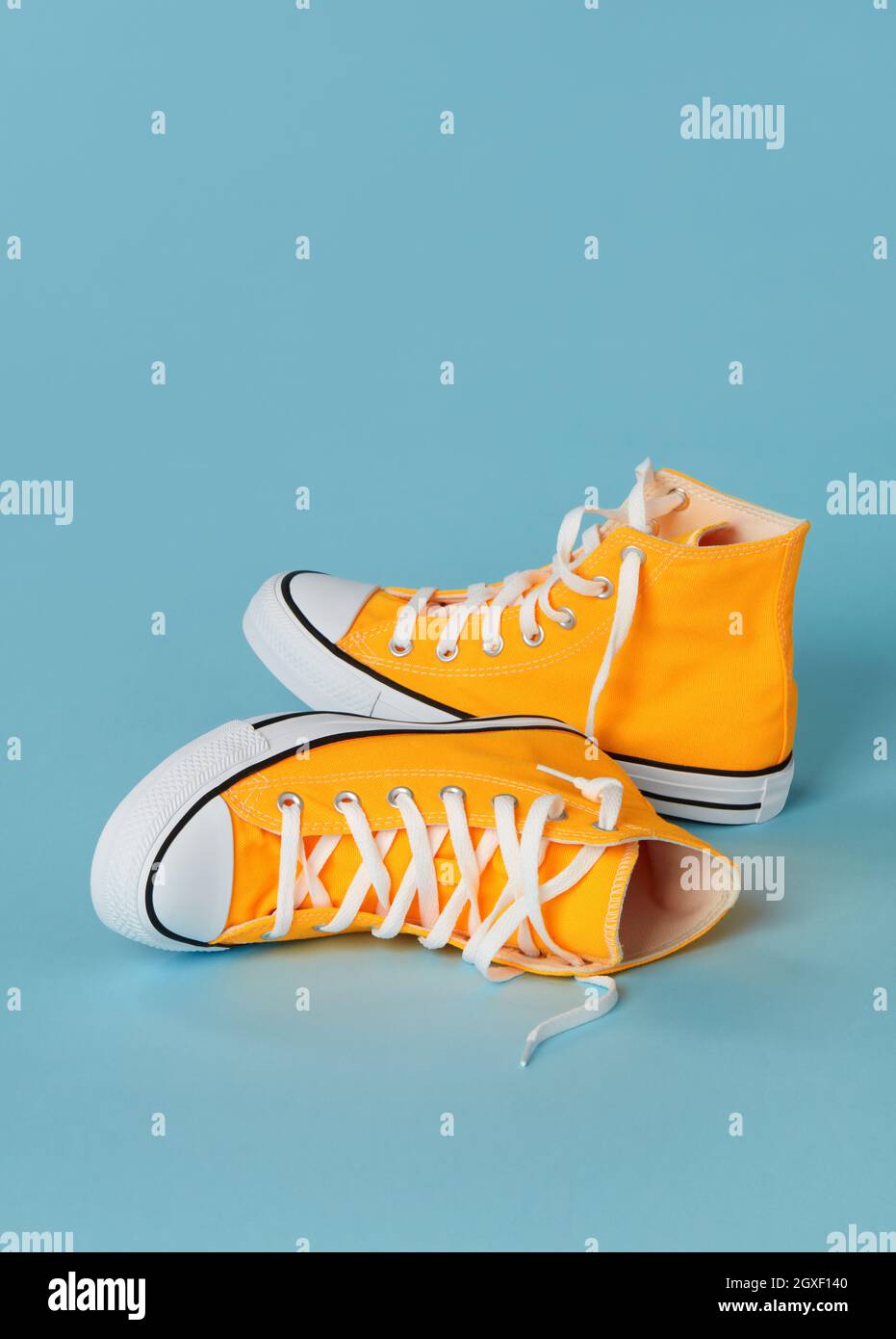 Yellow canvas shoes on blue background Stock Photo - Alamy