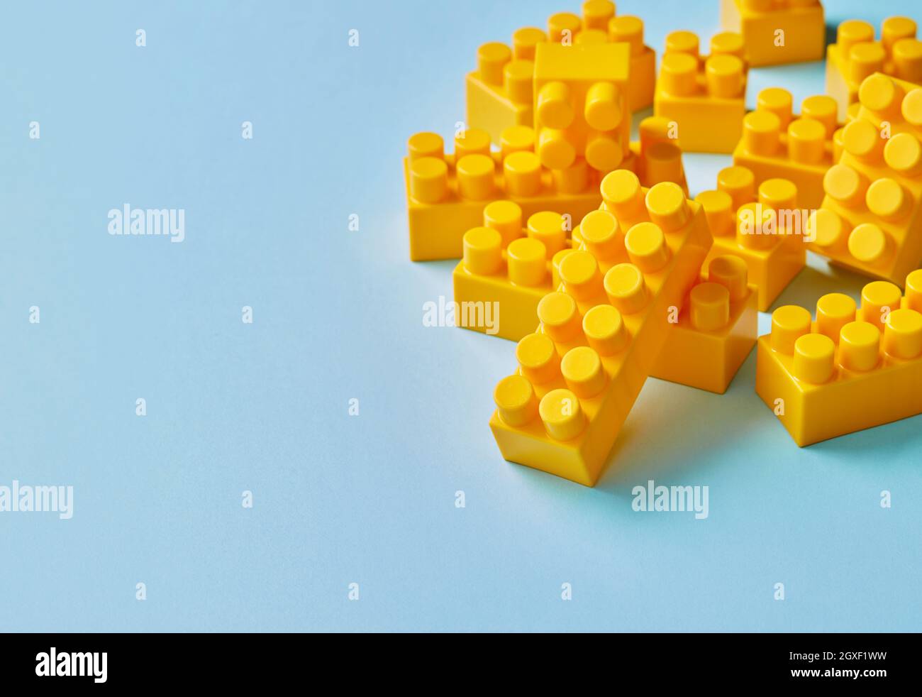 Plastic yellow toy blocks on blue background Stock Photo - Alamy