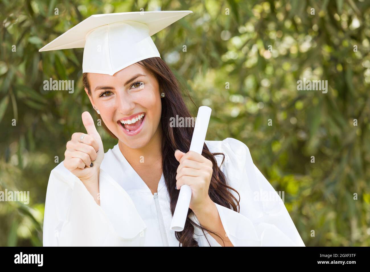 Mixed Race Thumbs Up Girl Celebrating Graduation Outside In Cap and ...