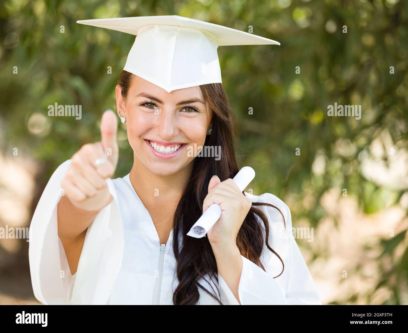 Mixed Race Thumbs Up Girl Celebrating Graduation Outside In Cap and ...