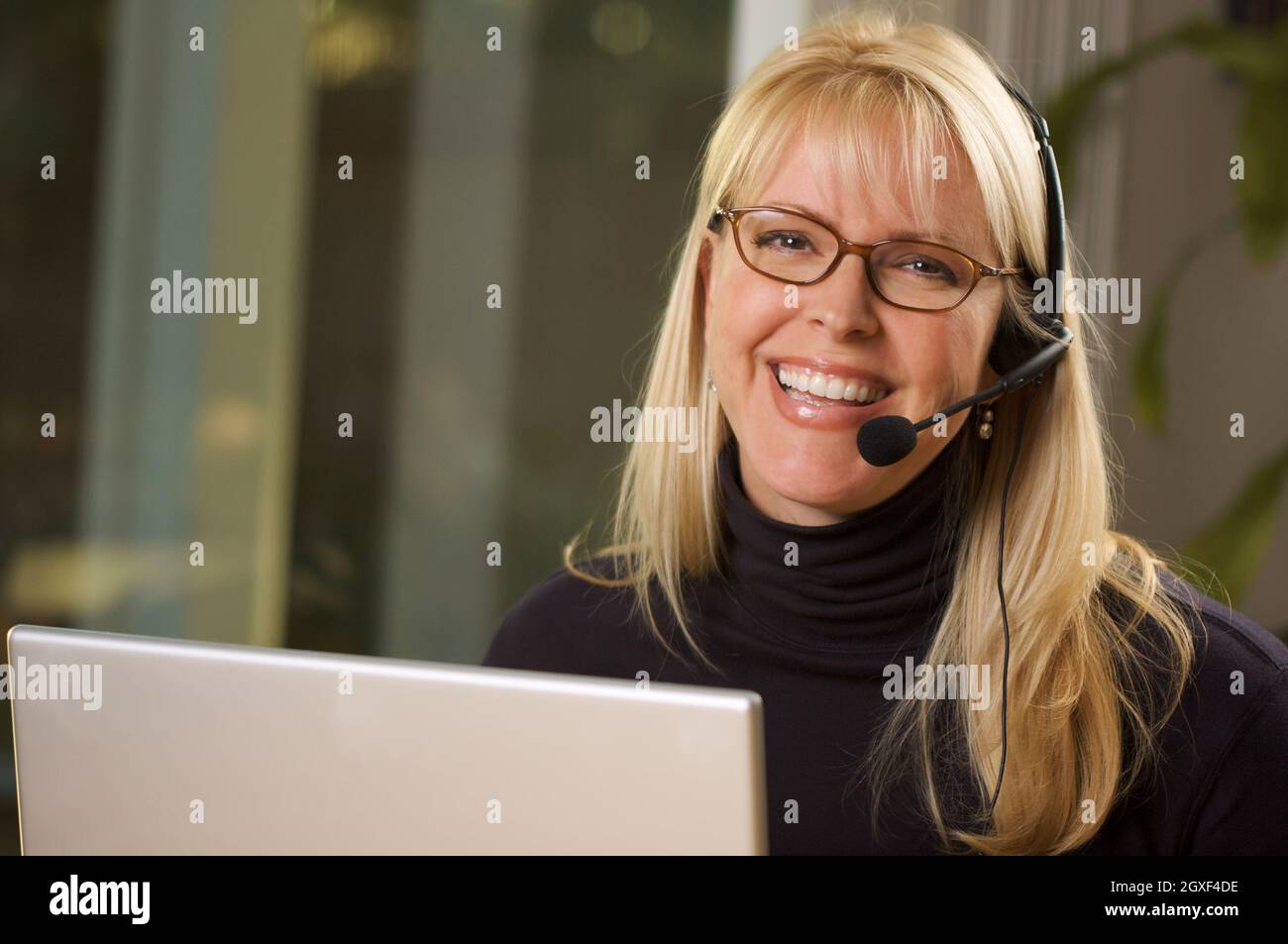 Attractive businesswoman smiles as she talks on her phone headset hi ...