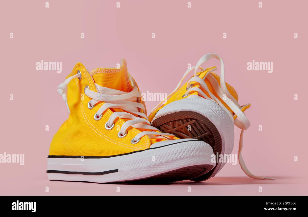 Yellow canvas shoes on pink background Stock Photo - Alamy