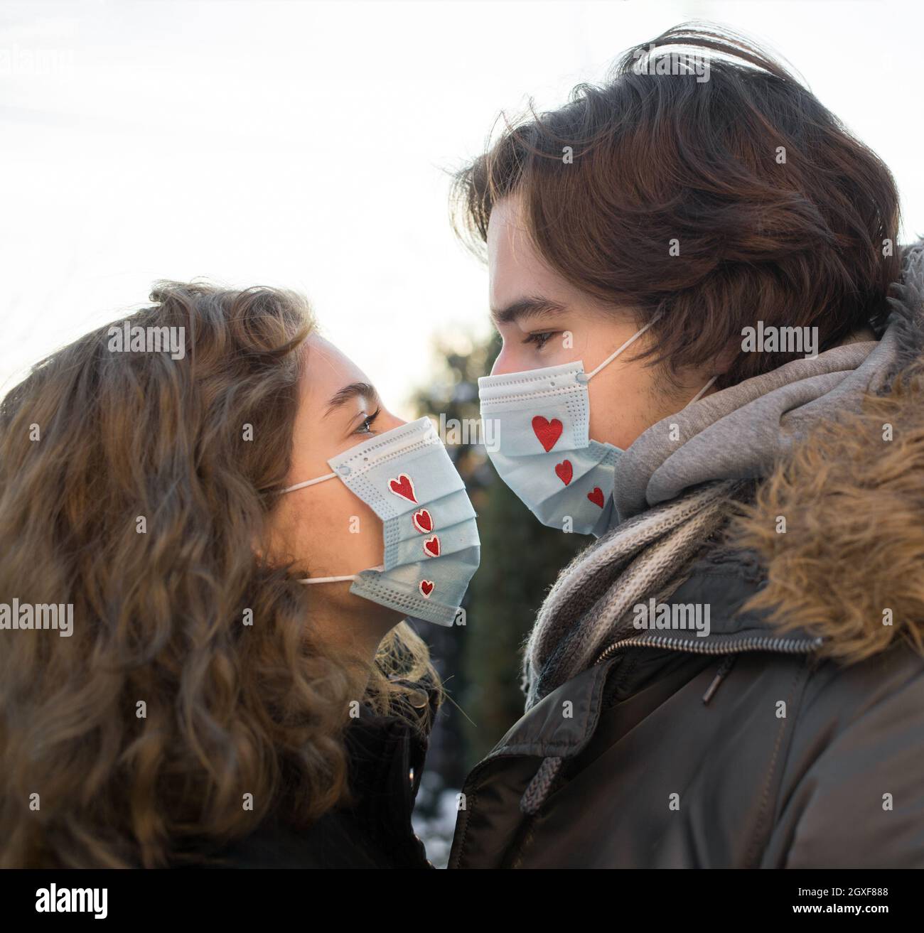 Young romantic couple in love wearing protective face masks with ...