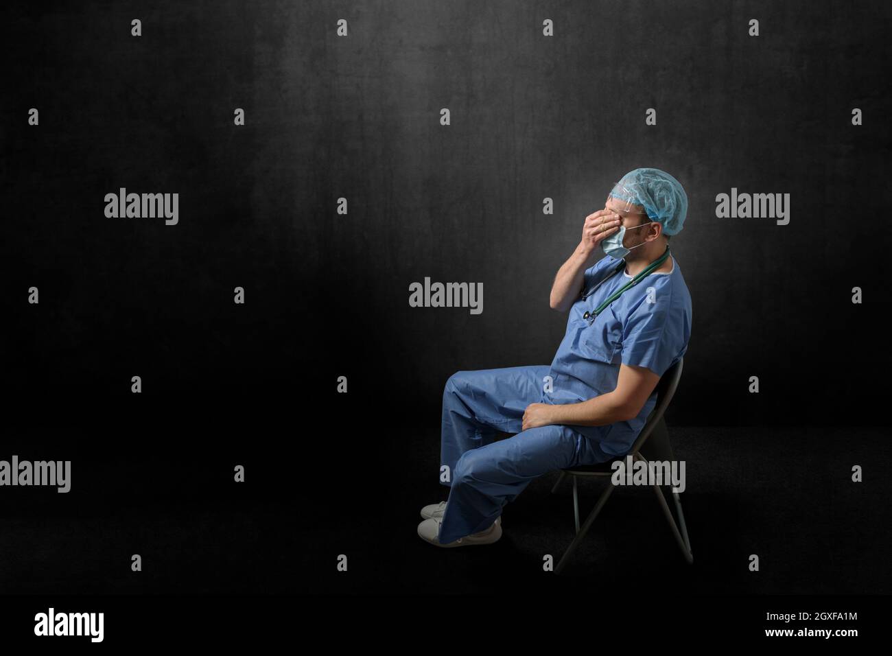 Side view of a sad, exhausted doctor sitting in a dark room Stock Photo ...