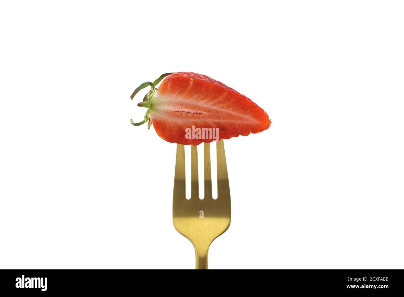 Half-cut strawberry on a golden fork isolated on a white background ...