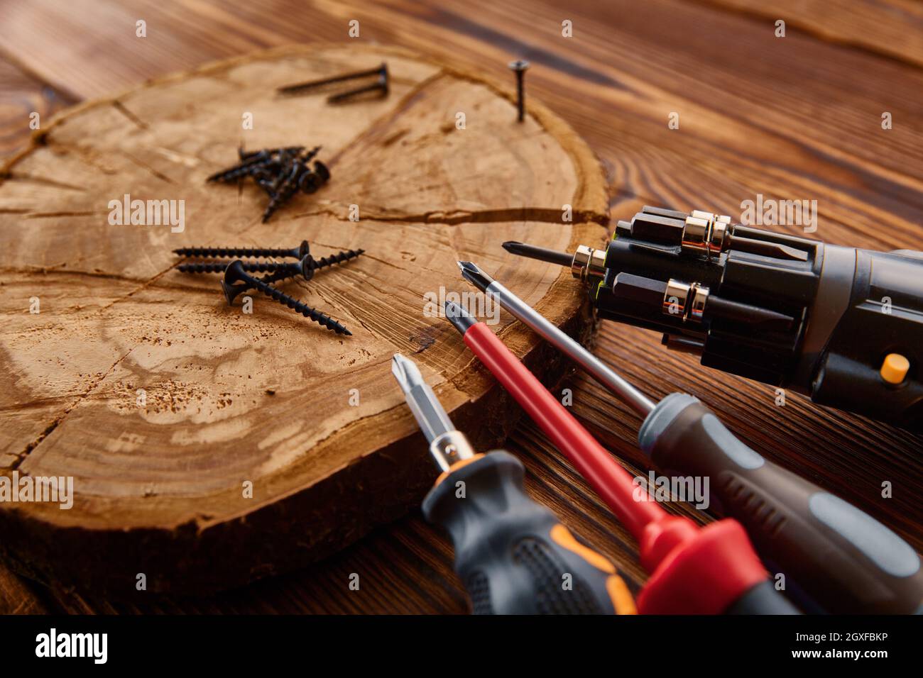 Screwdrivers and self tapping screws on stump, closeup, wooden ...