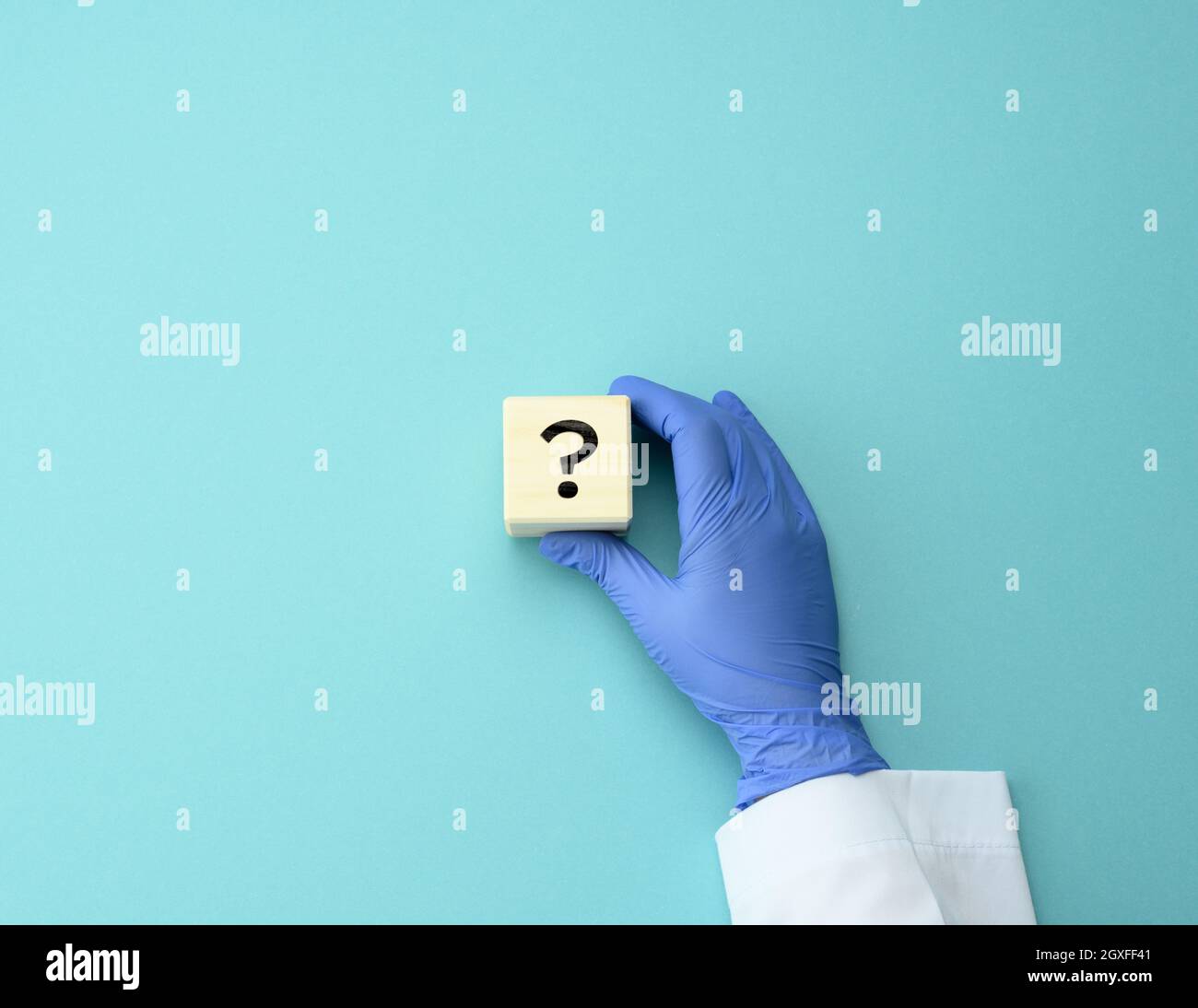 wooden cube with a question mark in the doctor's hand on a blue ...