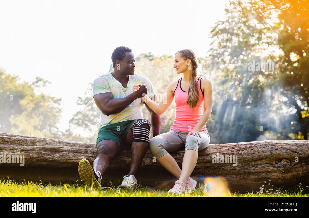 Fit young woman and her fitness instructor sitting on three trunk ...