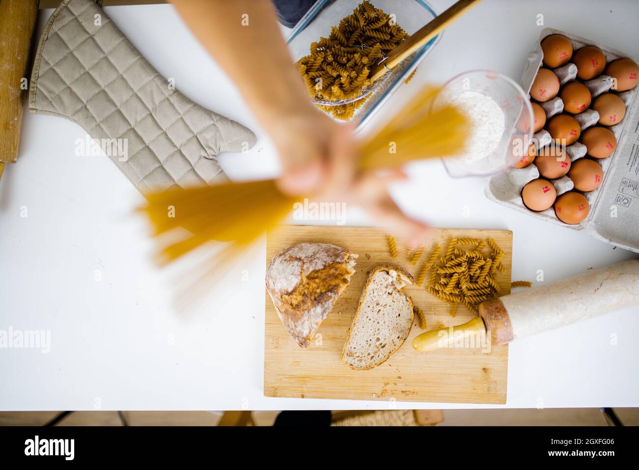 Blurry female hand holding uncooked spaghetti above ingredients on ...
