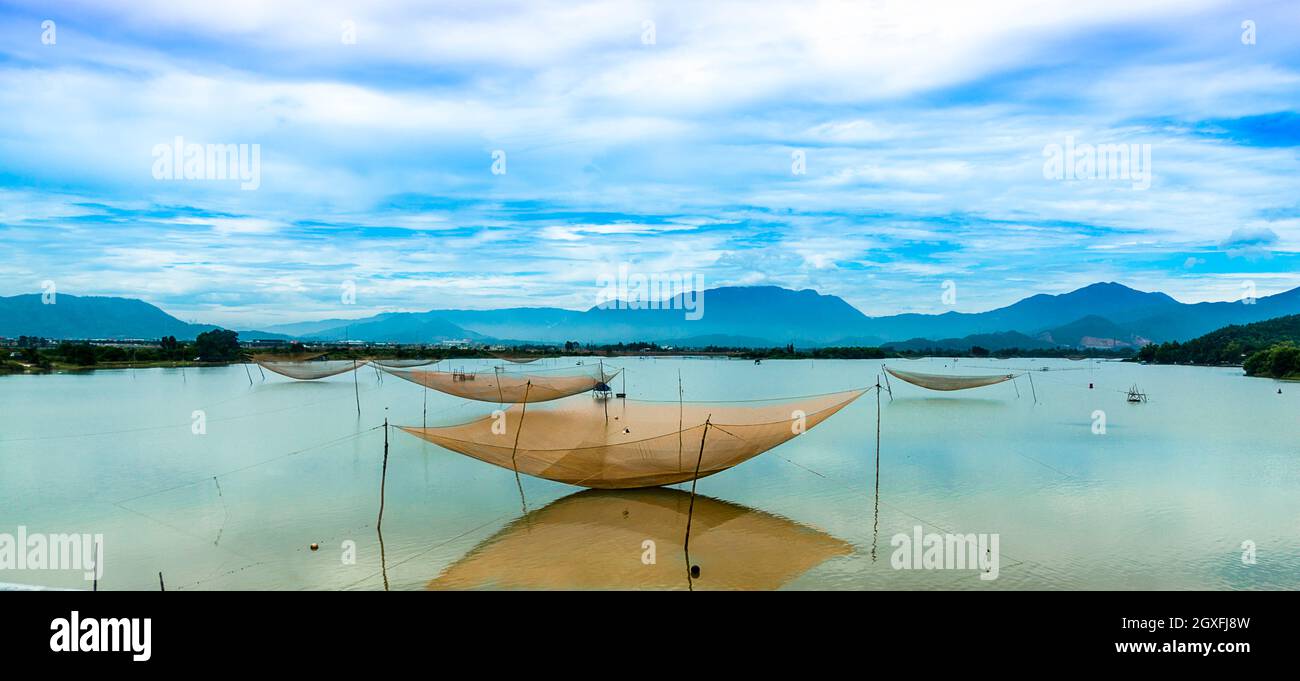 Coastal orange fishing nets in a calm bay with mountains and jungle in ...
