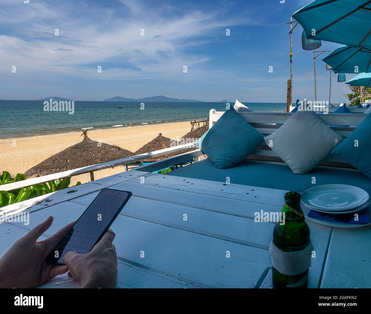 Sitting at a table at the beach with a smart phone under a Blue Sky ...