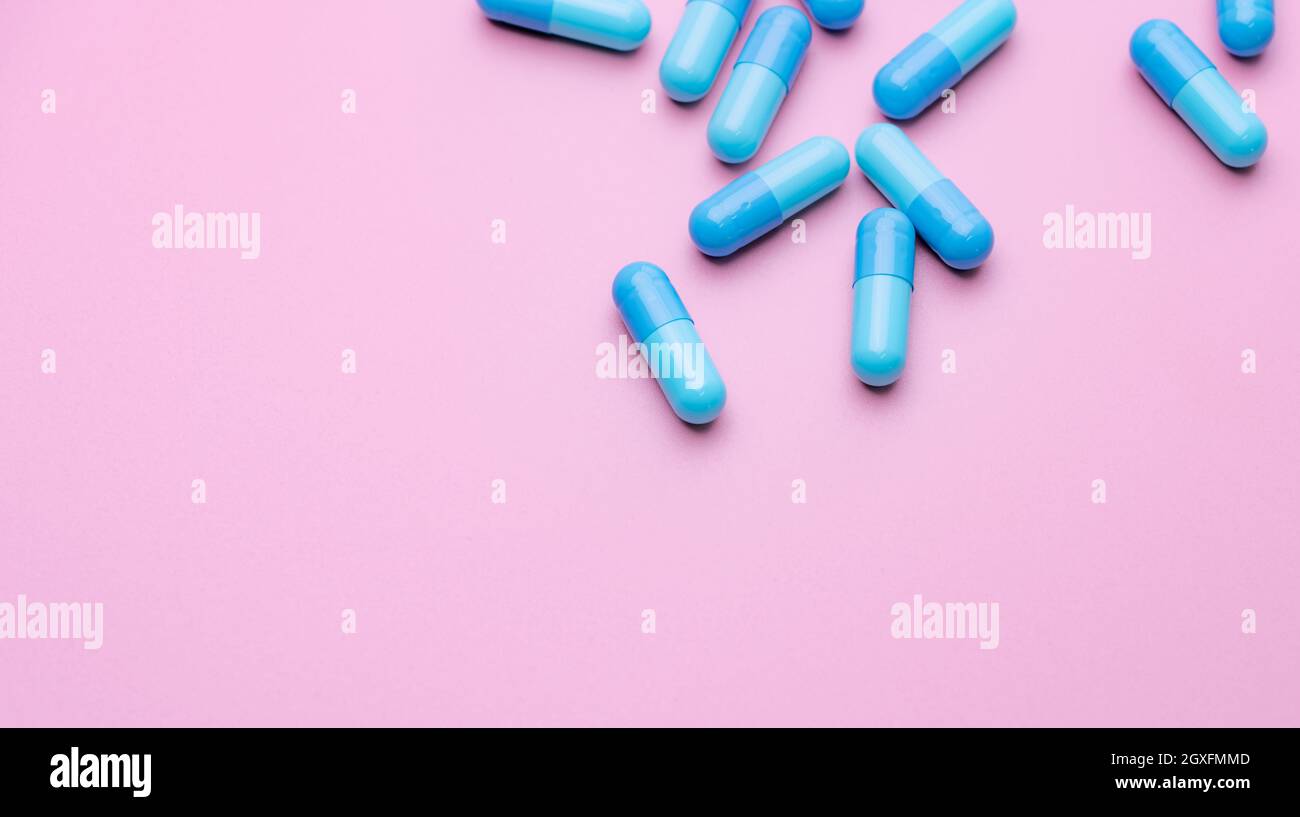 Blue capsule pills on pink background. Blue capsule pills with copy ...