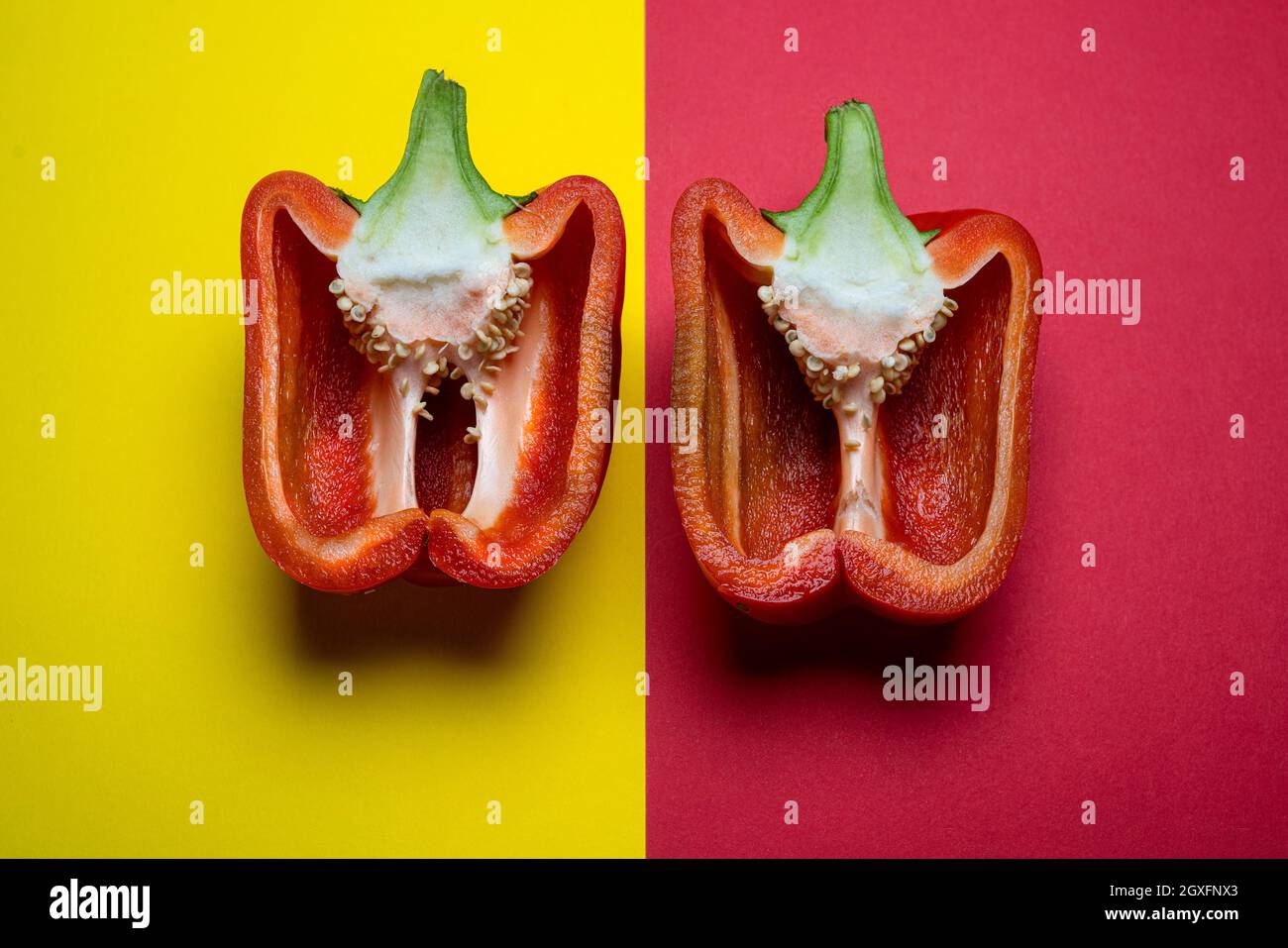 a red pepper cut in half and arranged on a colored surface Stock Photo ...