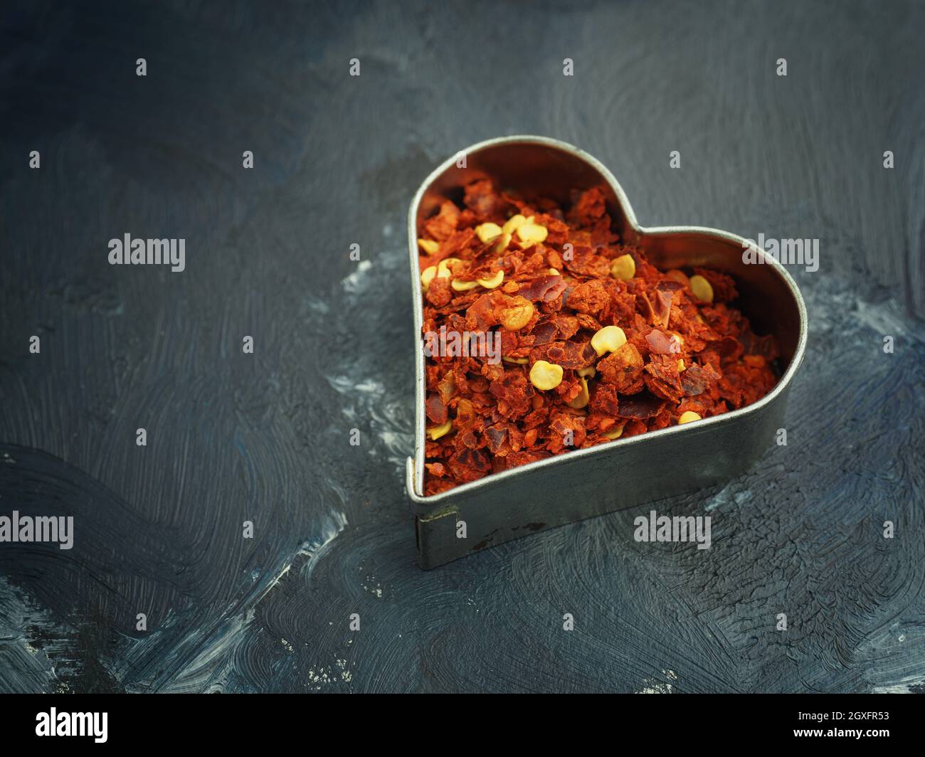 Hot organic chili flakes in a heart shaped cookie cutter, spicy ...