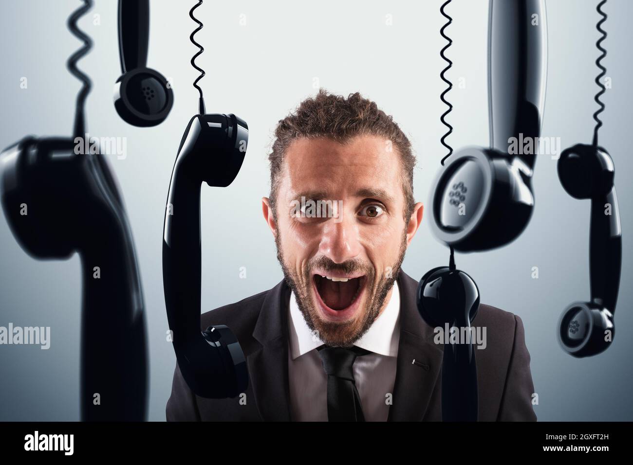 Angry businessman screams between black handsets phones Stock Photo - Alamy