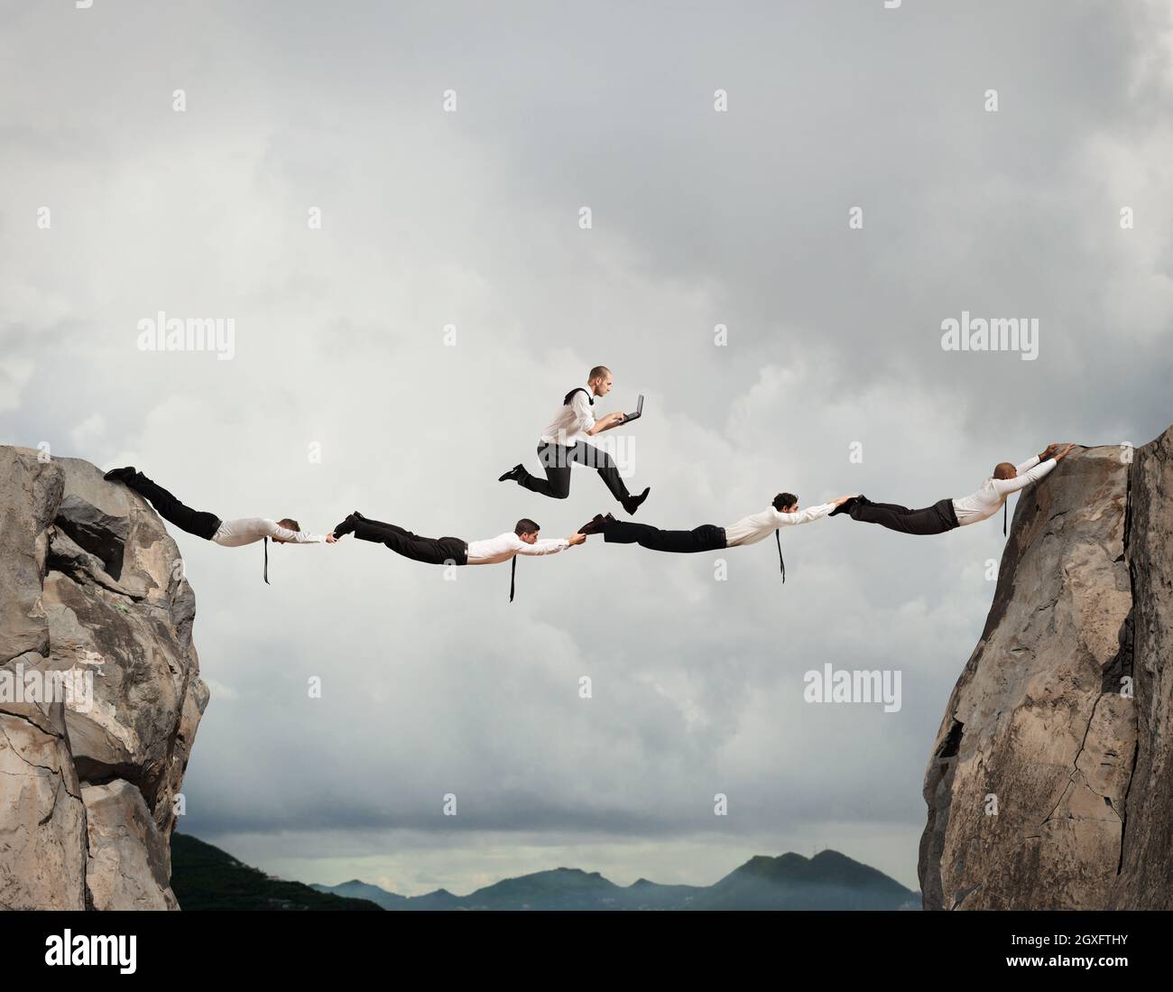 Businessmen working together to form a bridge between two mountains ...