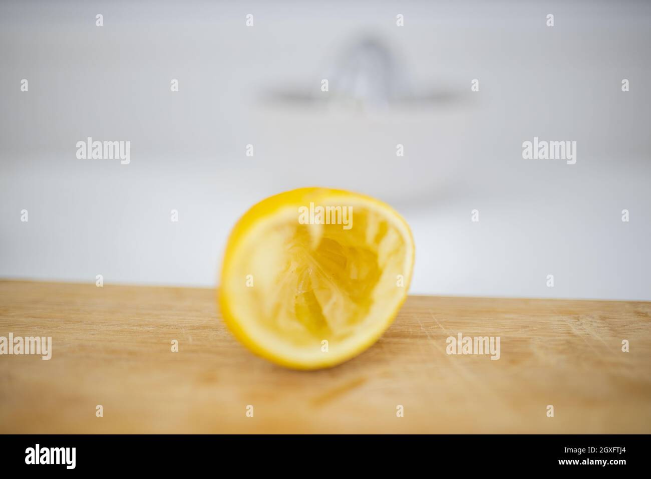 Empty lemon peel on wooden cutting board with white blurry background ...