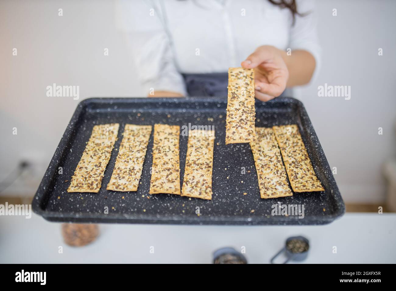 Female hand holding black tray of Swedish multi-seed crispbread ...