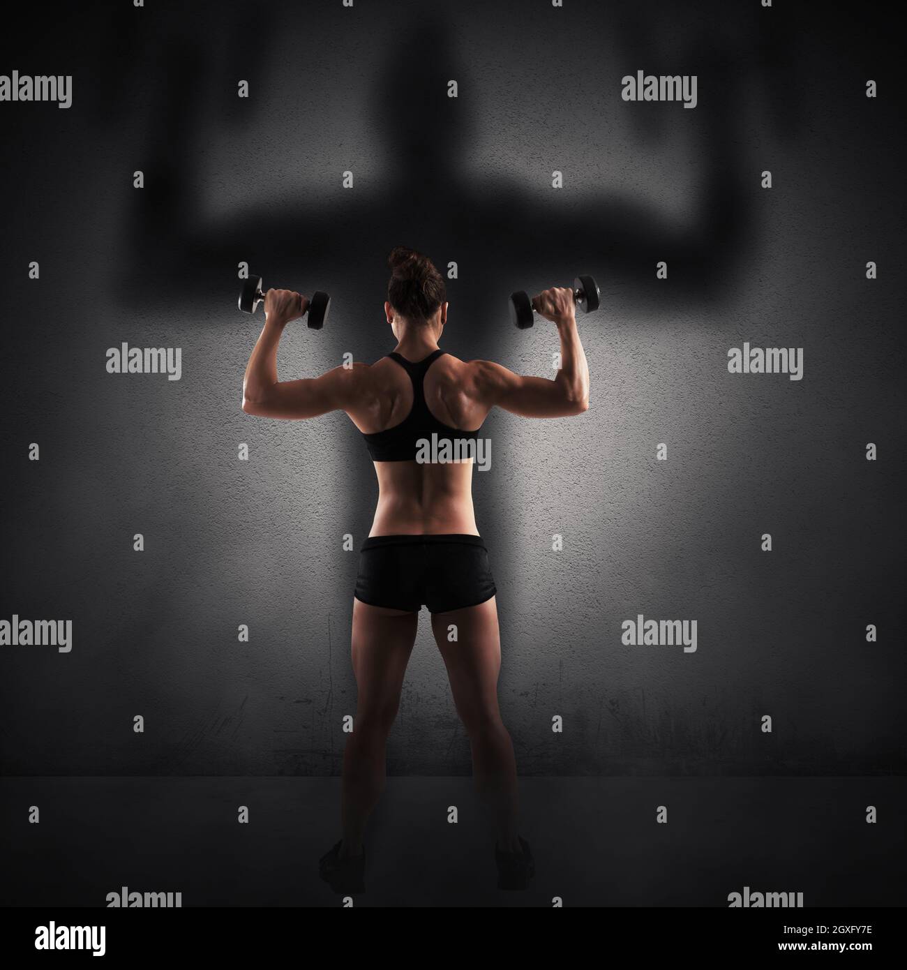 Muscular woman looks at her big shadow Stock Photo - Alamy