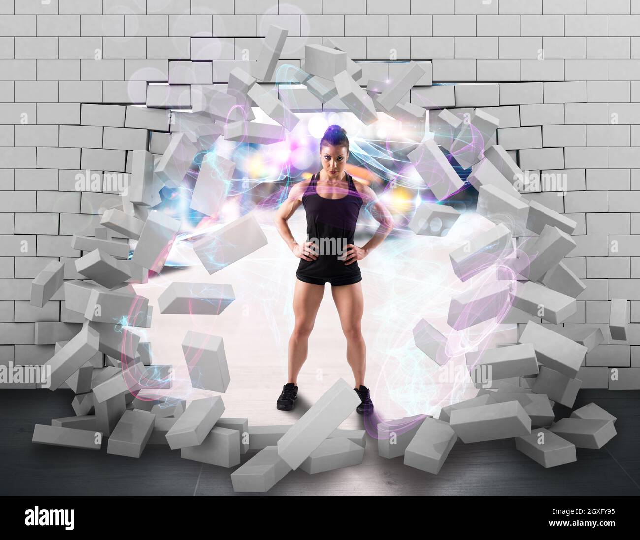 Muscular woman behind a broken brick wall Stock Photo - Alamy