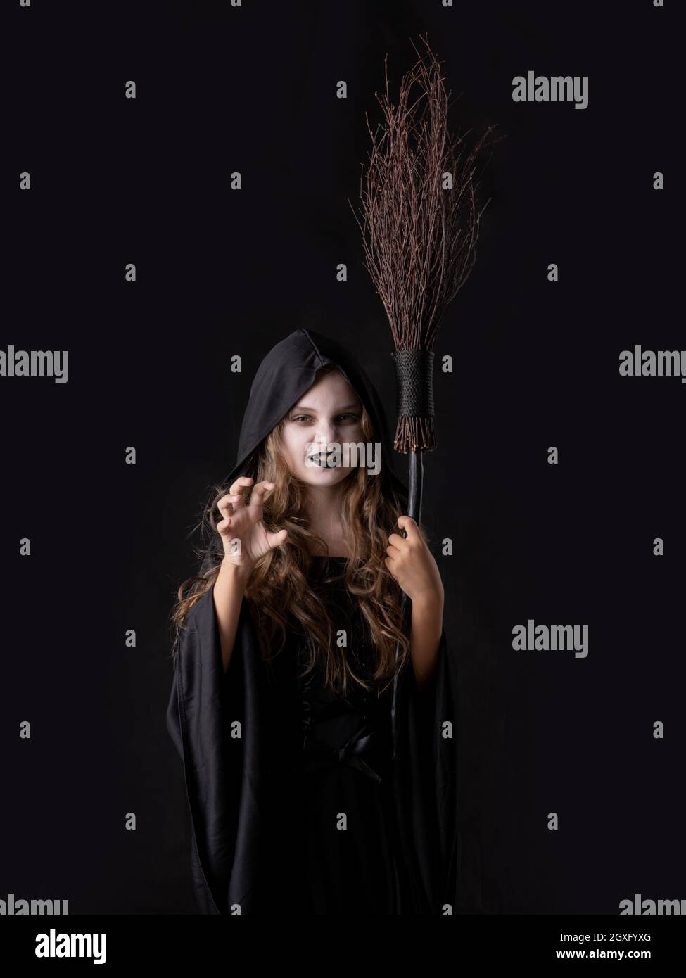 Girl in halloween evil angry witch costume grin snarl hold broom ...