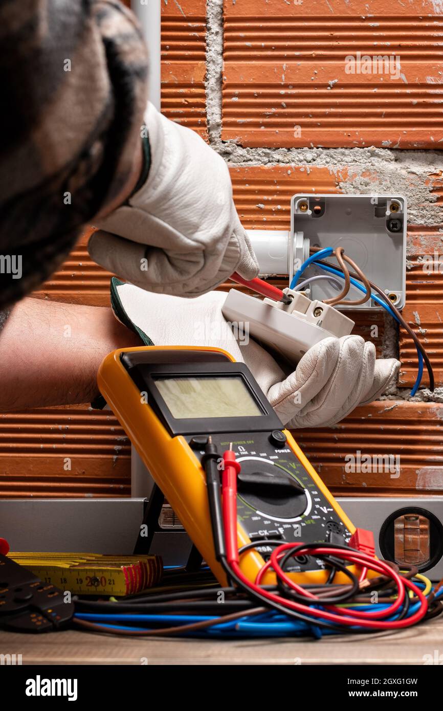 Electrician worker with a screwdriver fixes the cable in the terminal ...