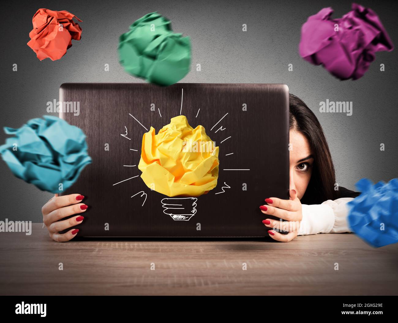 Businesswoman is protected behind the computer screen from paper balls ...