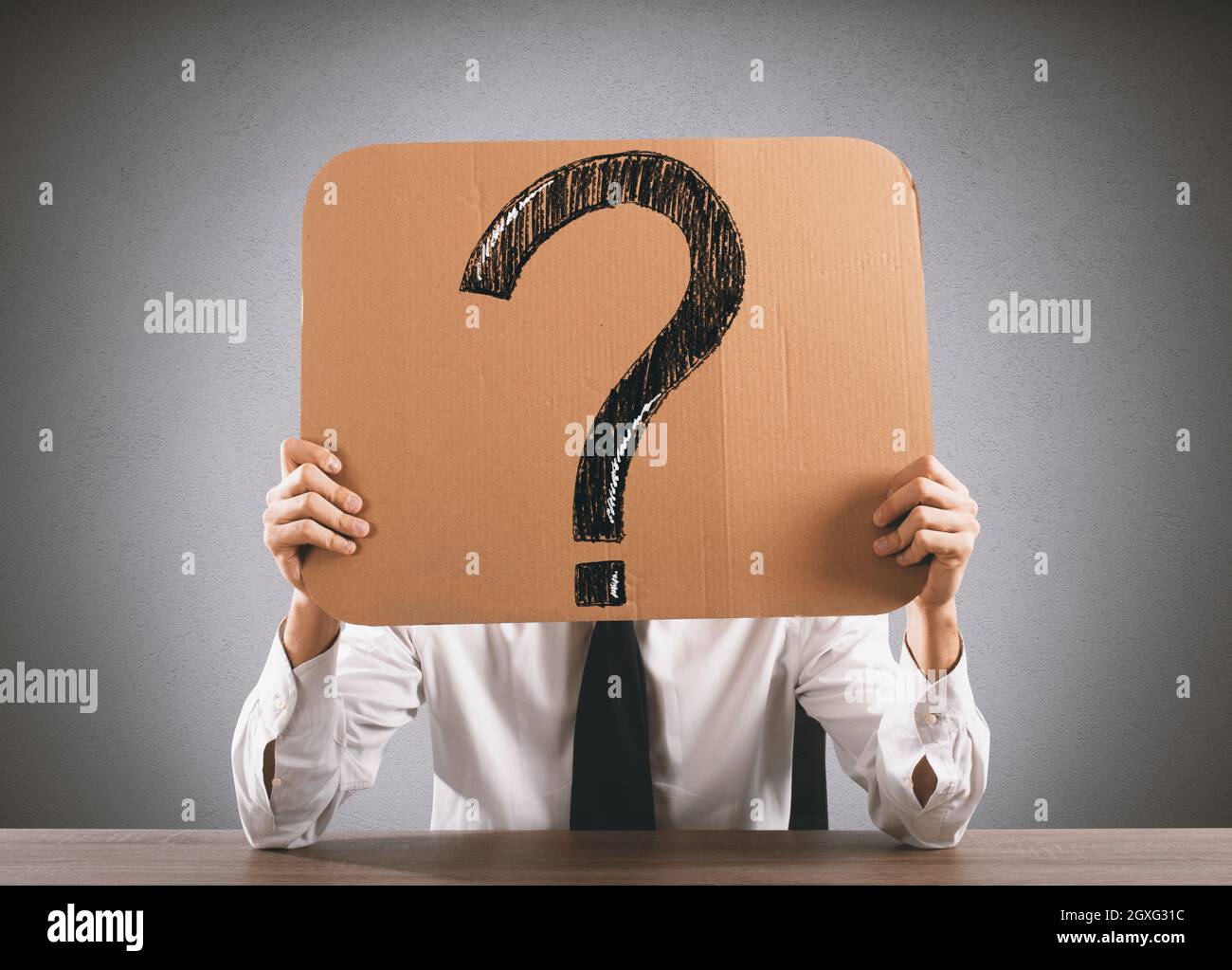 Businessman in the office holds a cardboard with big question mark ...