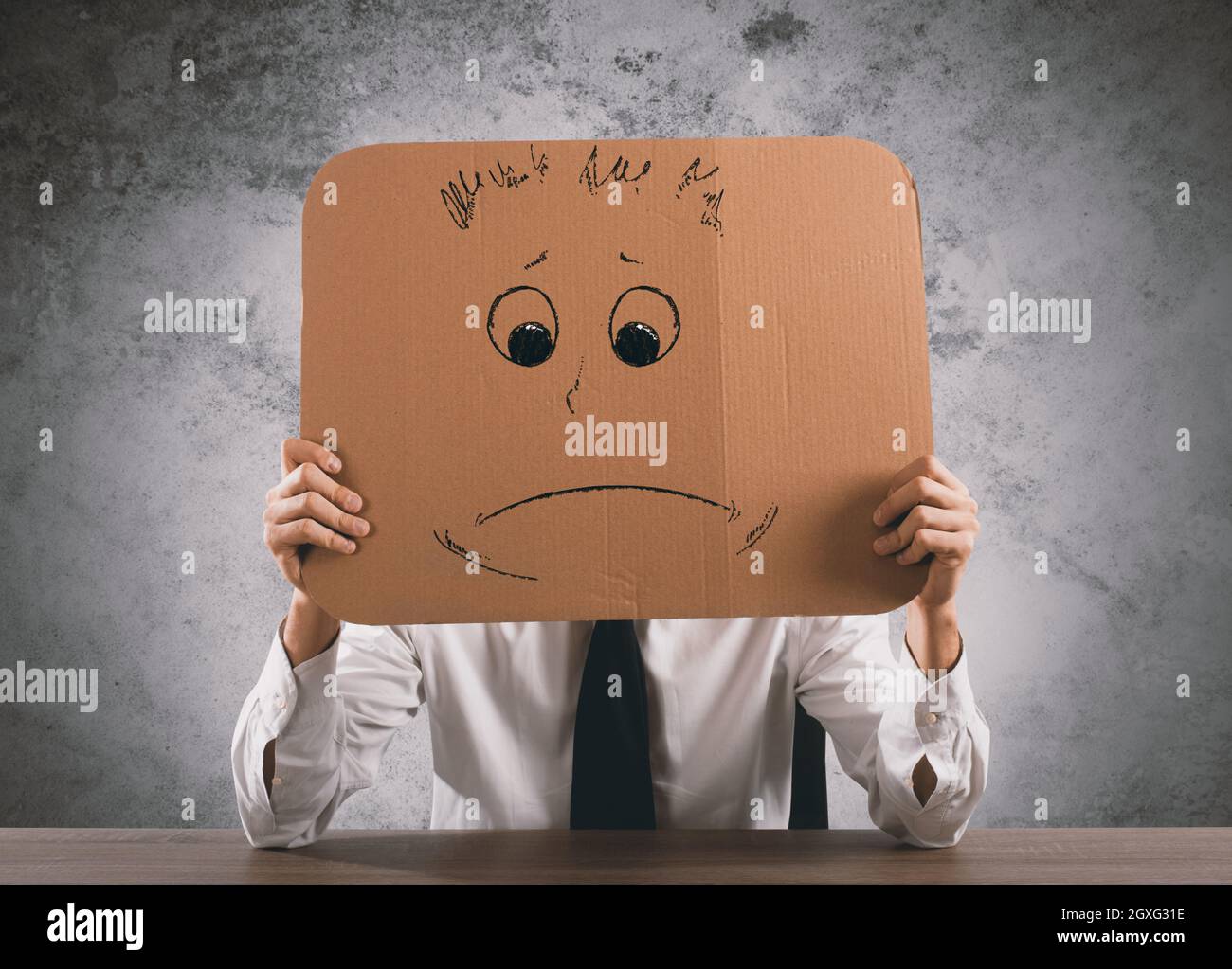Businessman in the office holds a cardboard with a sad face Stock Photo ...