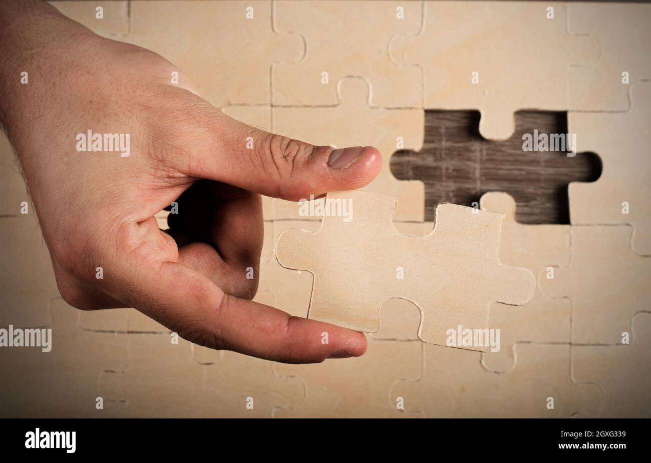 Businessman complete a puzzle inserting a missing piece Stock Photo - Alamy