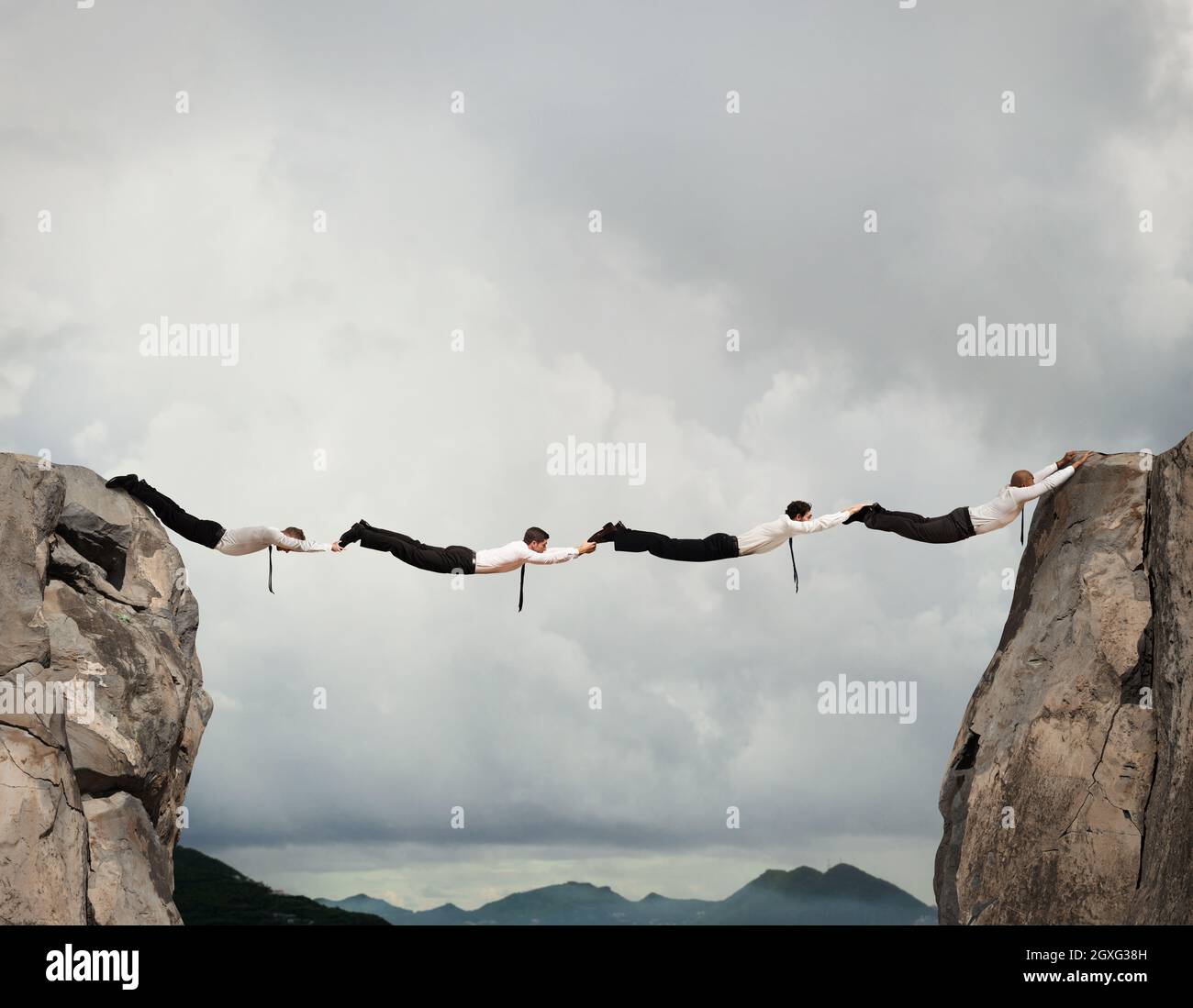 Businessmen working together to form a bridge between two mountains ...