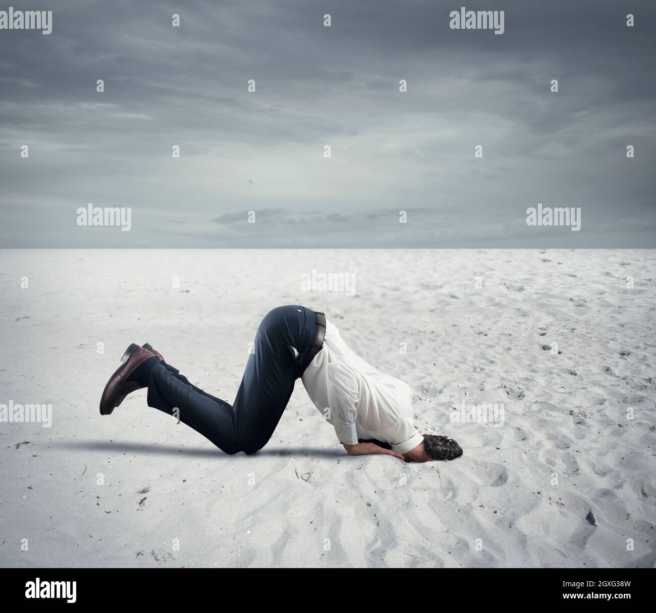 Afraid businessman hides his head under the ground like an ostrich ...