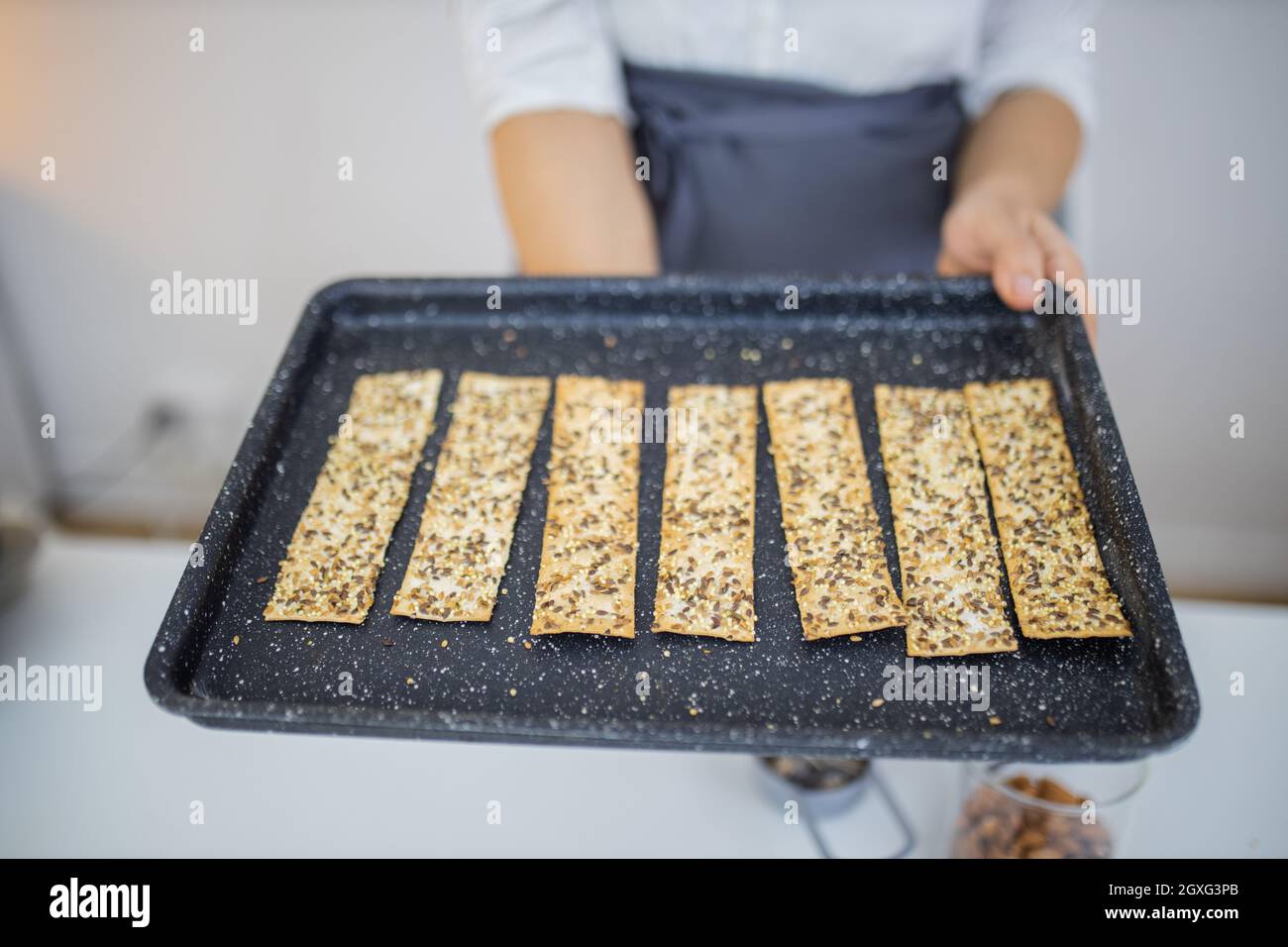 Female hand holding black tray of Swedish multi-seed crispbread ...