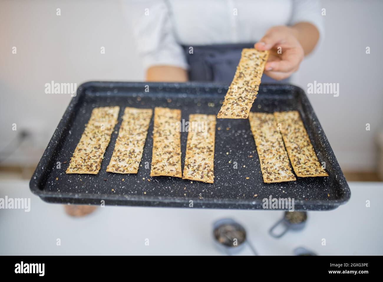 Female hand holding black tray of Swedish multi-seed crispbread ...